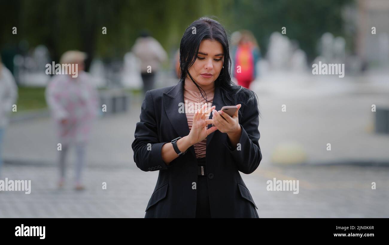 Close-up businesswoman stands outdoors in city near roadway holding ...