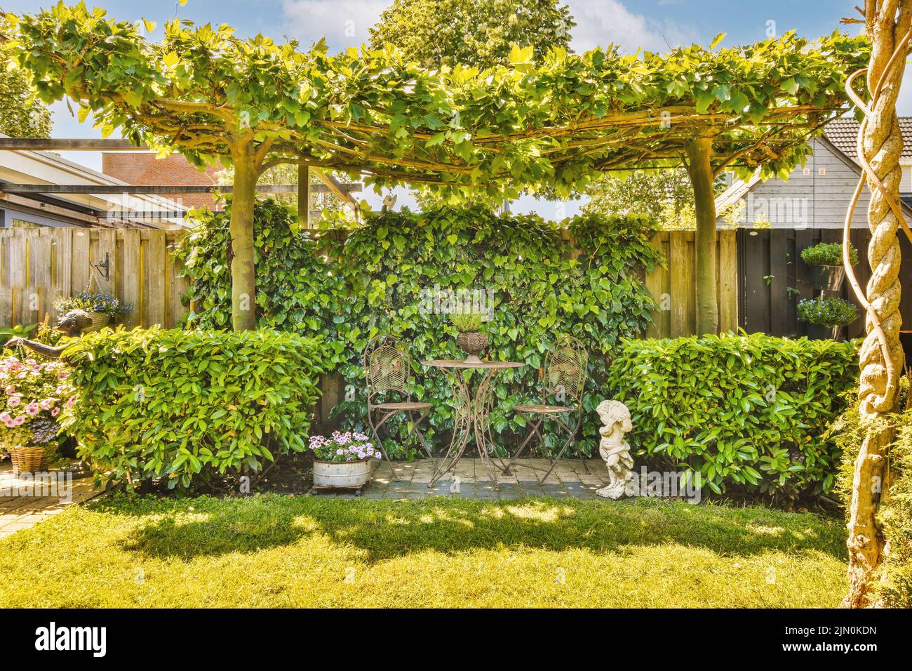 Neat paved patio with sitting area and small garden near wooden fence ...