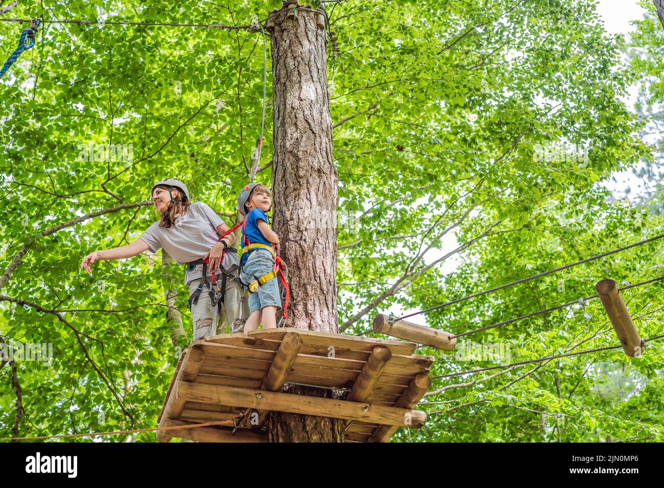 Mother and son climbing in extreme road trolley zipline in forest on ...