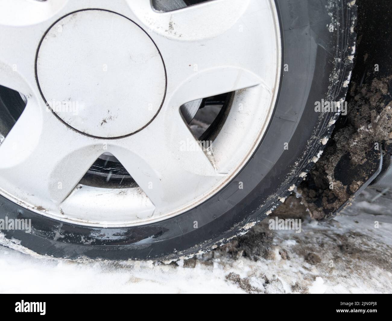car wheel on slow covered surface at winter day, flat cast silver disc ...