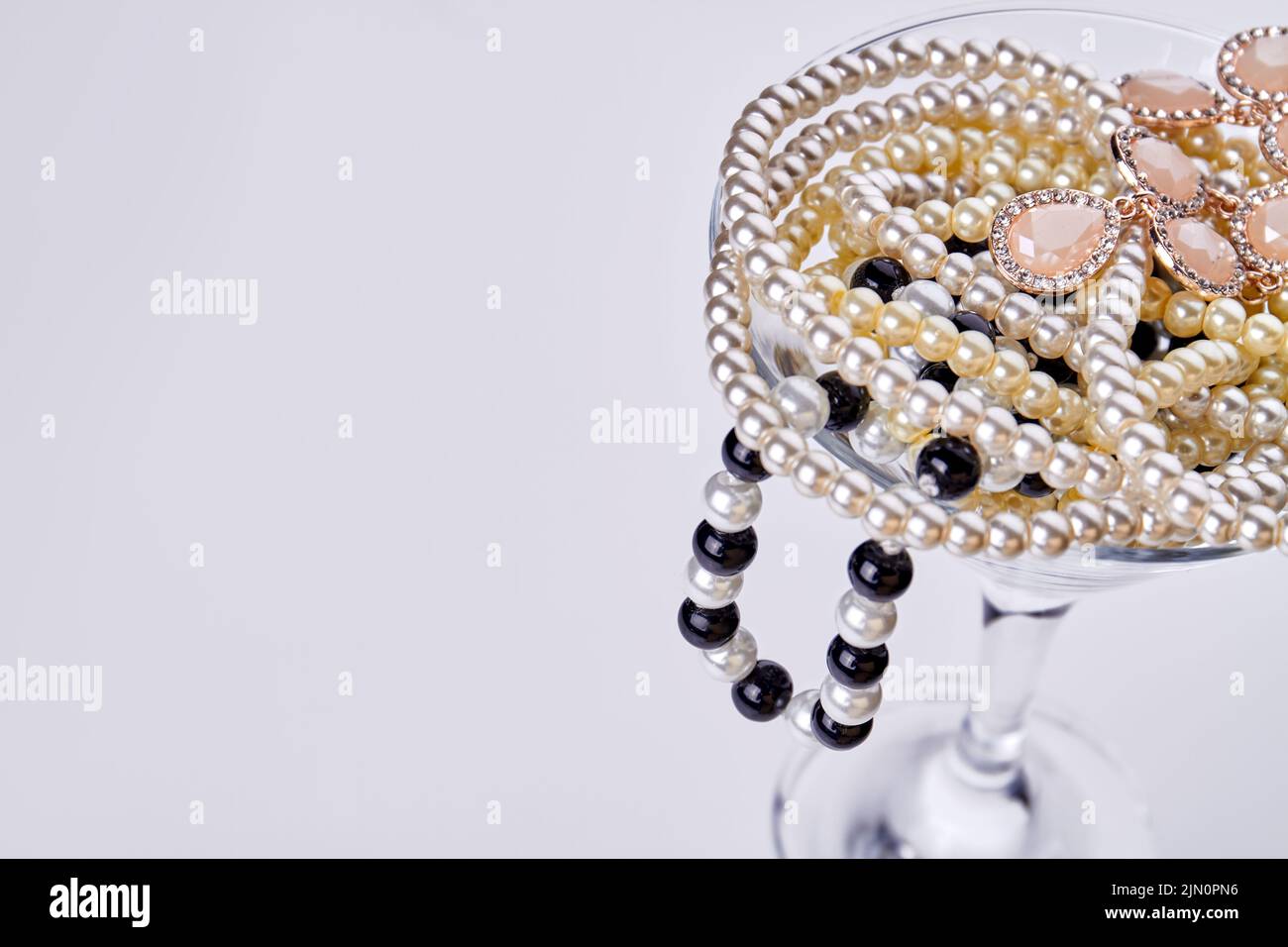 Cocktail glass with jewelry and pearls and copy space. Isolated on ...