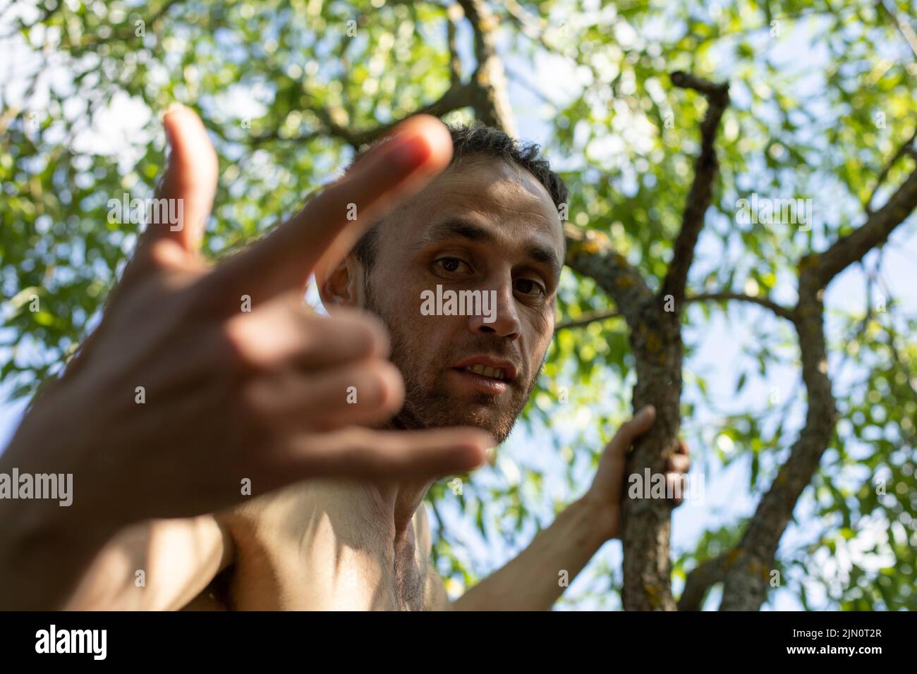 Guy looks into frame and shows goat. Man in tree. Rest in wild. Jungle ...