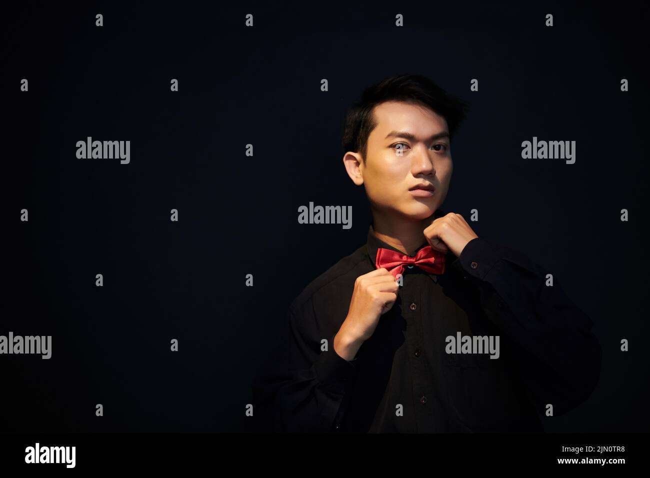 Portrait of young Asian man adjusting redbow tie on his neck Stock Photo - Alamy