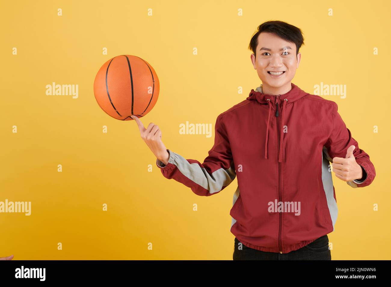Portrait of smiling young man spinning basketball ball on finger and ...