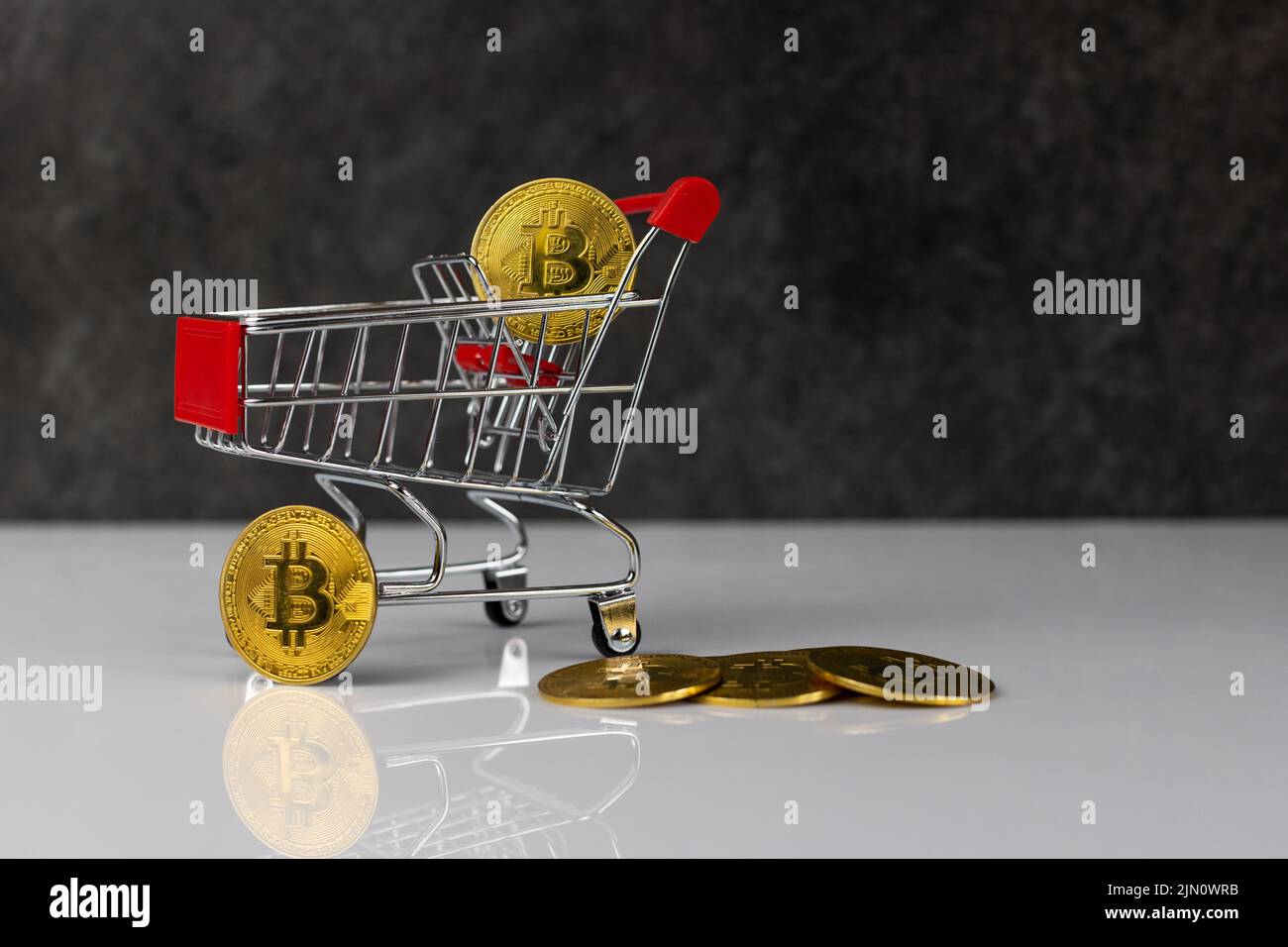 Bitcoin in shopping trolley on dark grey background in white table ...