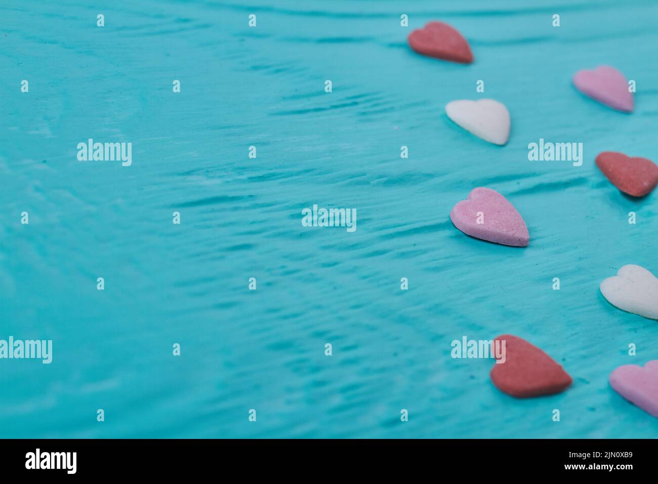 Close up colored candy hearts and copy space. Blue relief background ...