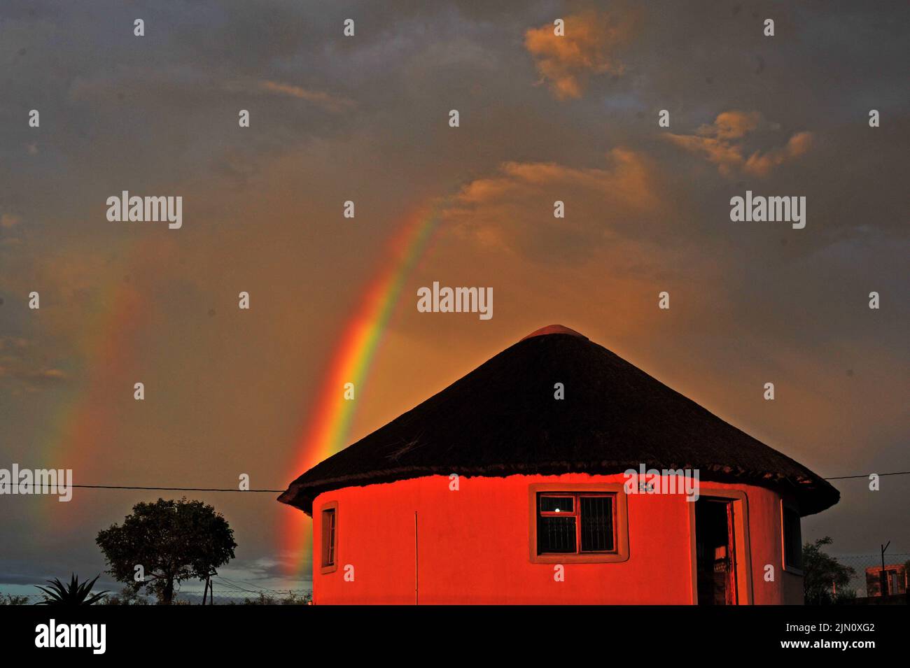 A beautiful rainbow over grass thatched rondavels in Limpopo province ...