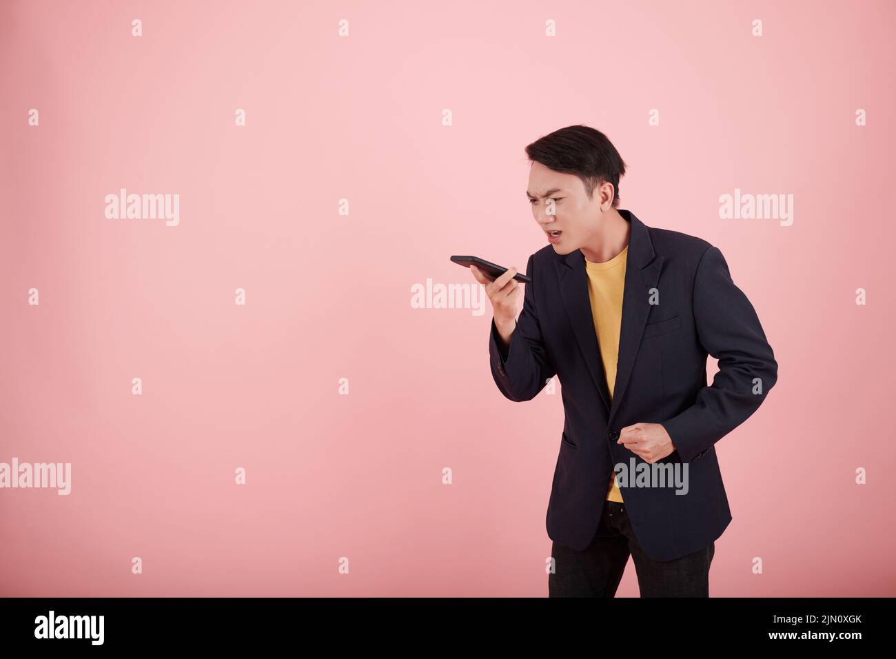 Angry irritated young businessman recording voice message for coworker ...