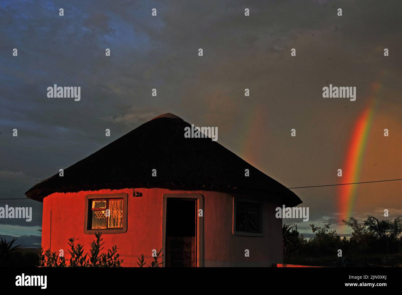 A beautiful rainbow over grass thatched rondavels in Limpopo province ...