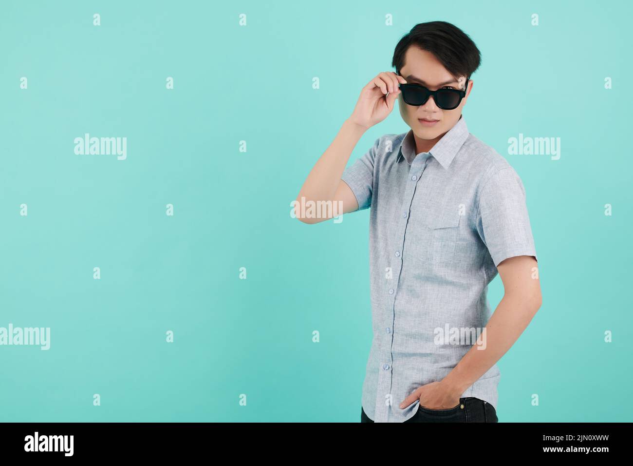Cool stylish young man taking off sunglasses and looking at camera ...