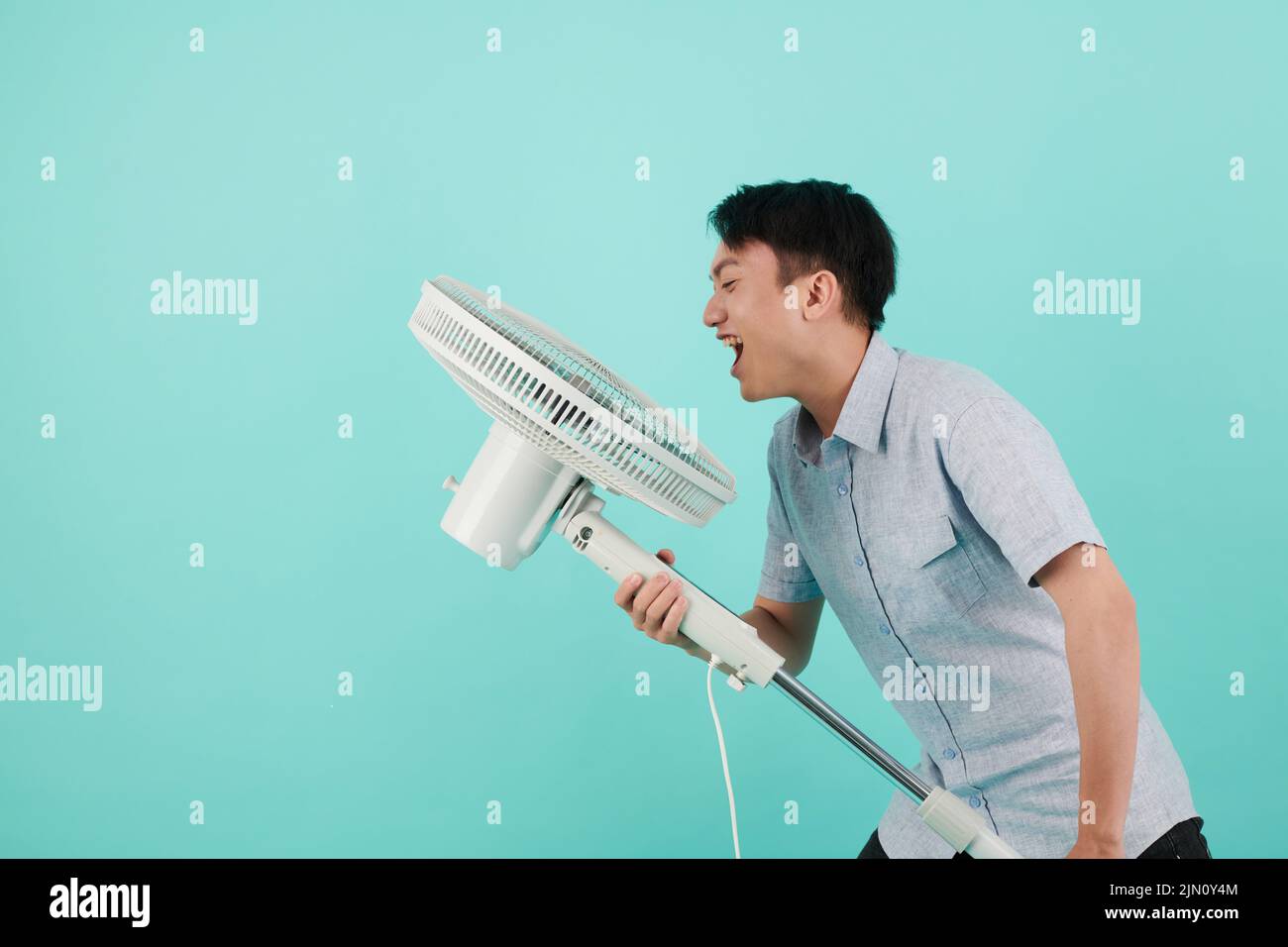 Young man shouting in fan as microphone, isolated on turquoise Stock ...