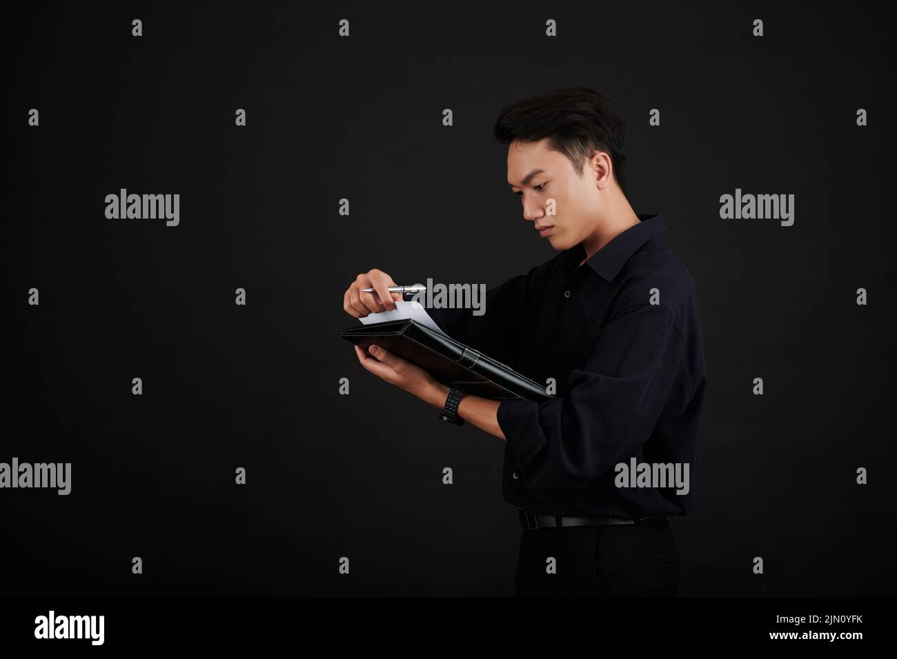 Serious young entrepreneur reading and signing documents, isolated on ...