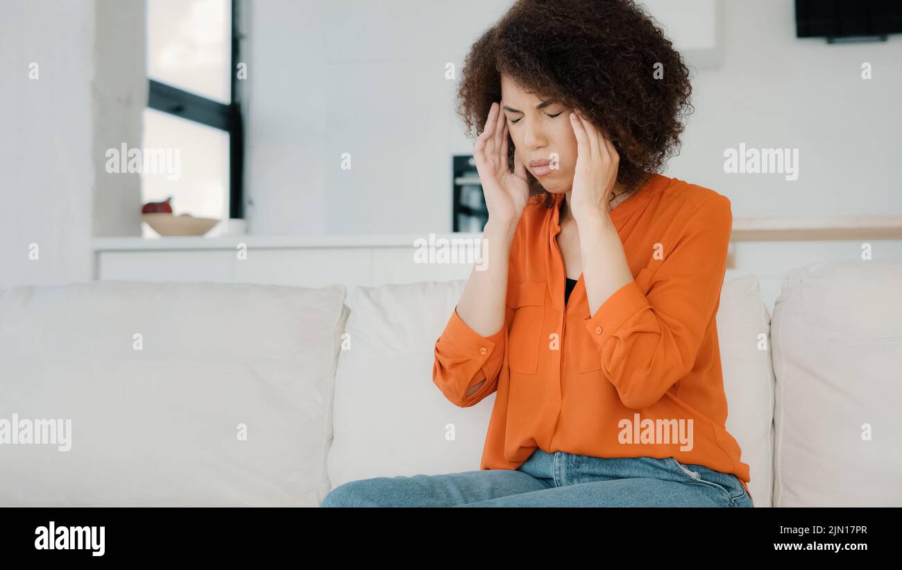 African American girl with curly hair woman sitting at home on couch ...
