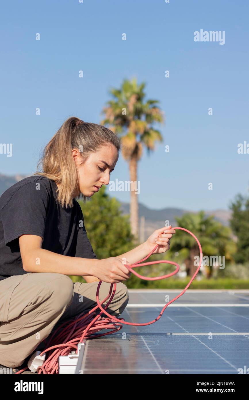 Vertical view of young woman engineer installing a solar photovoltaic ...