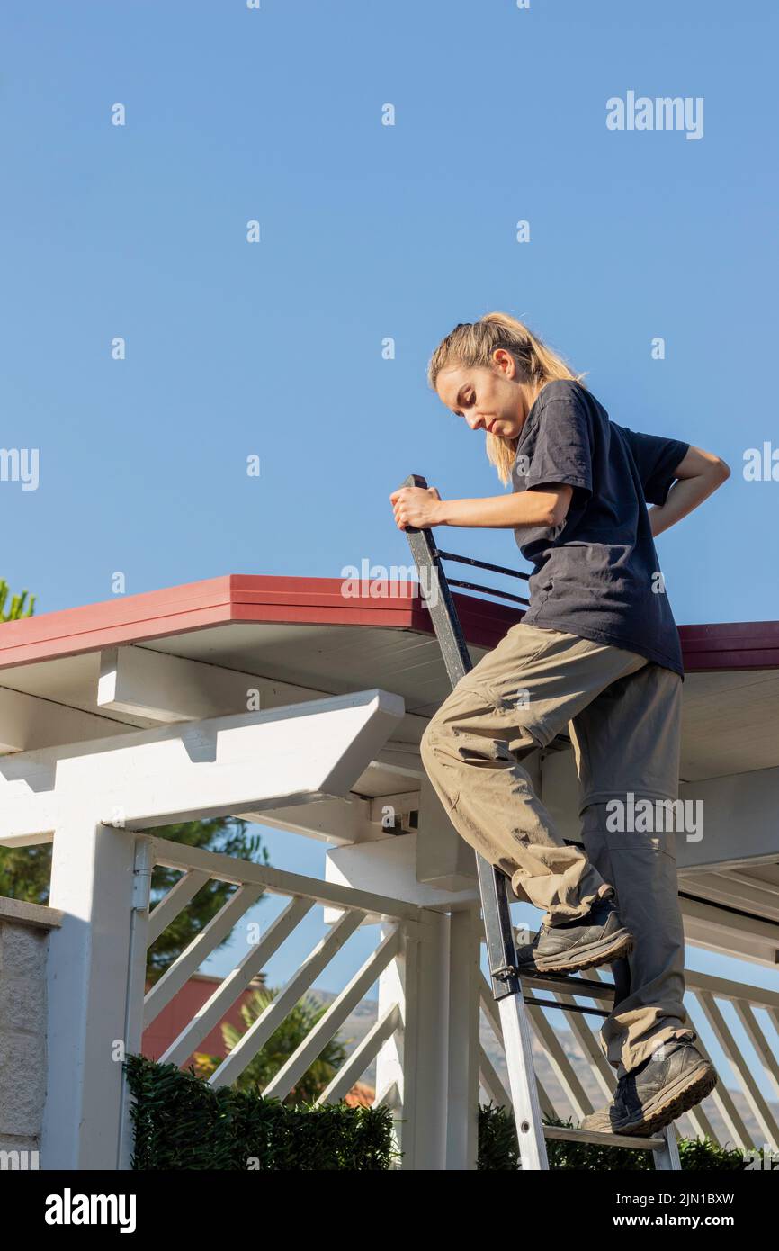 Vertical view of young working labourer woman stepping on a ladder ...