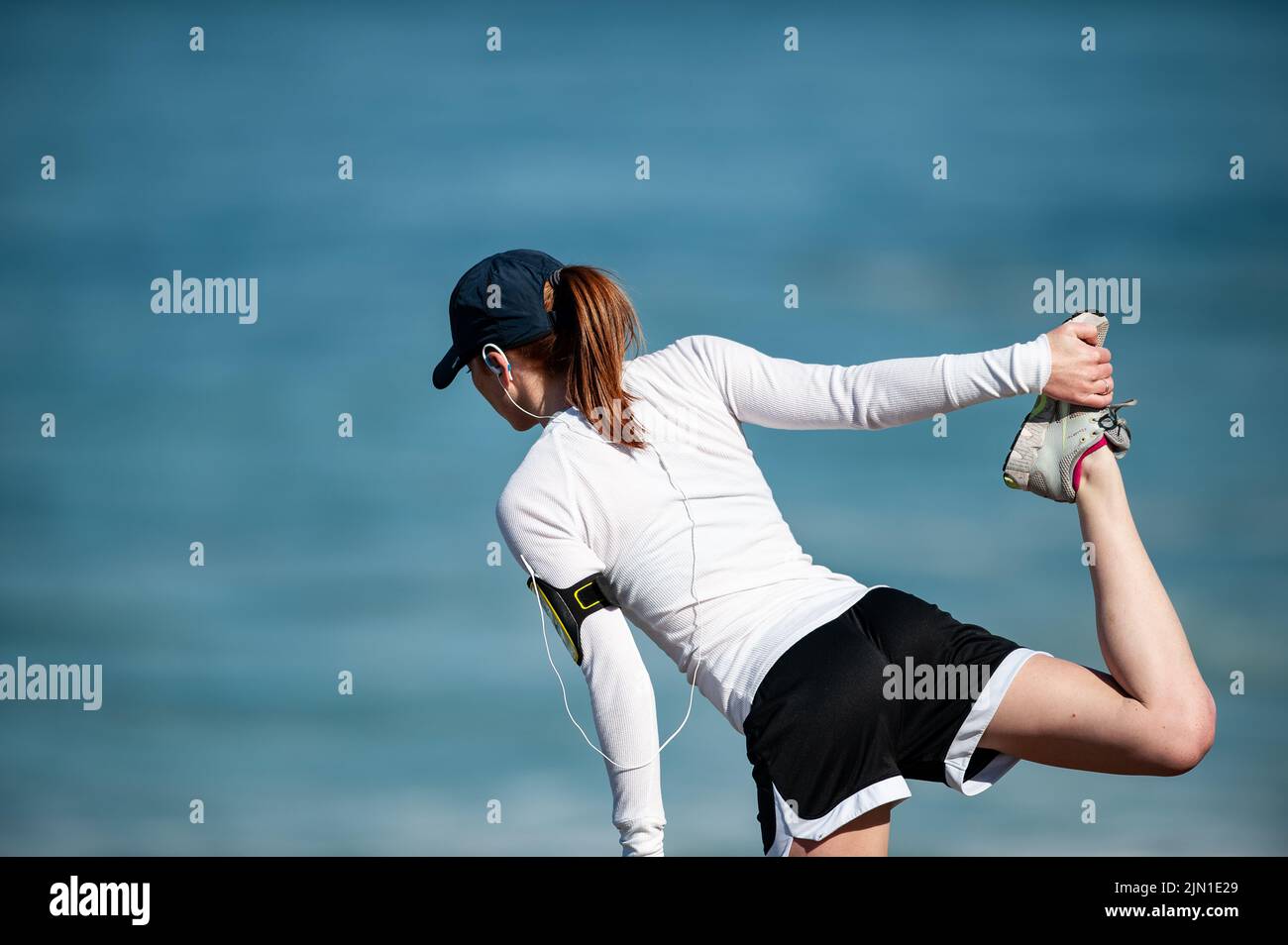 Stock image of a woman stretching before her morning beach run. Runner ...