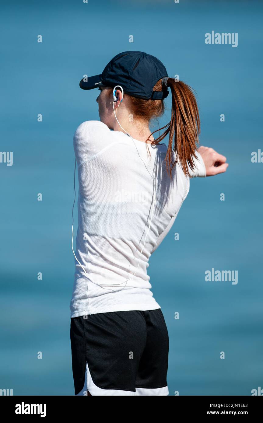Stock image of a woman stretching before her morning beach run. Runner ...