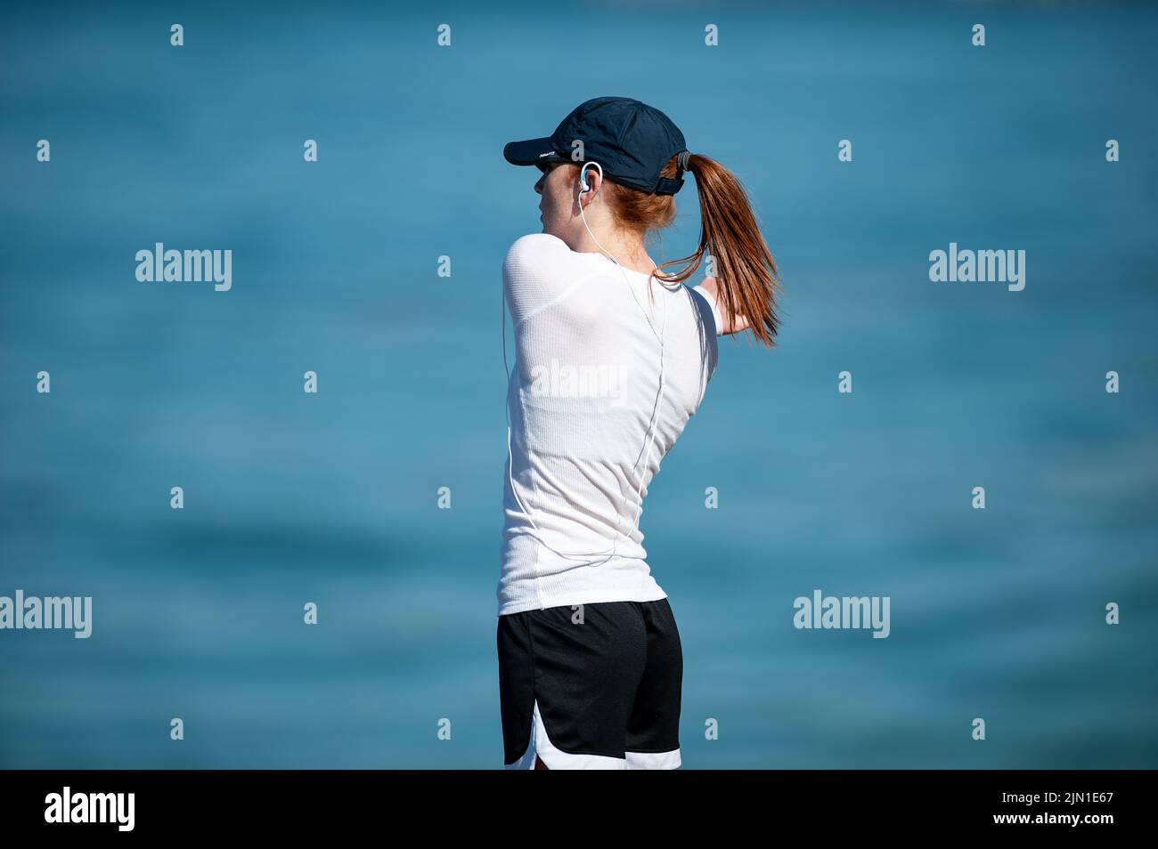 Stock image of a woman stretching before her morning beach run. Runner ...