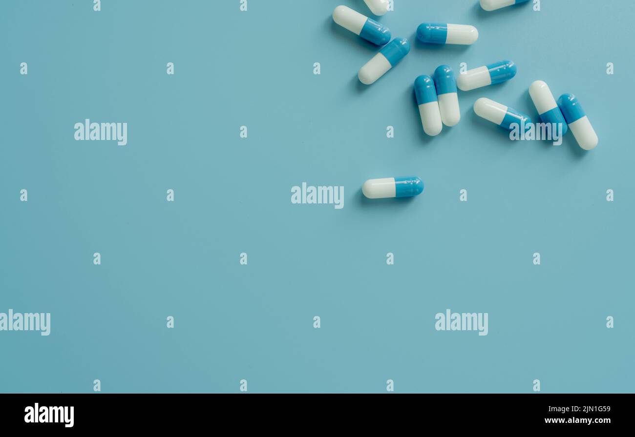 Top view blue-white antibiotic capsule pills on blue background ...