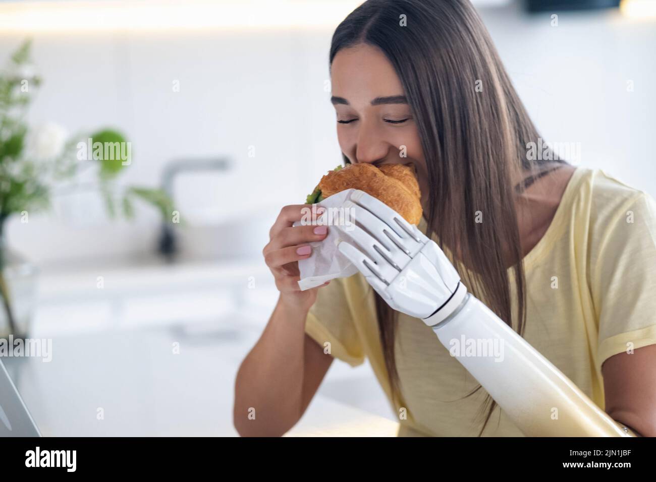Girl using prosthetic arm while eating at home, woman with disability ...