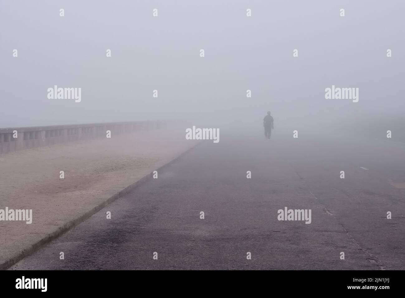 man walking alone in the morning fog by the sea Stock Photo - Alamy