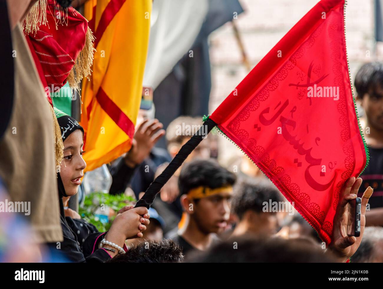 Srinagar, India. 08th Aug, 2022. A Shia Muslim girl holds an Alam ...