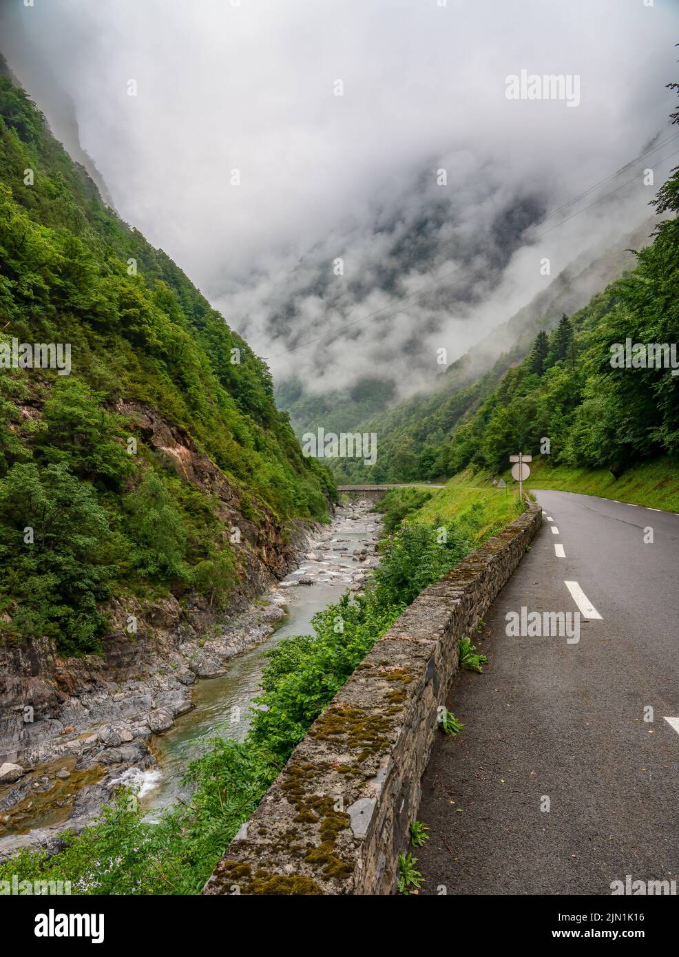 road and river flow down a mountain gorge, cloud rolling down the ...