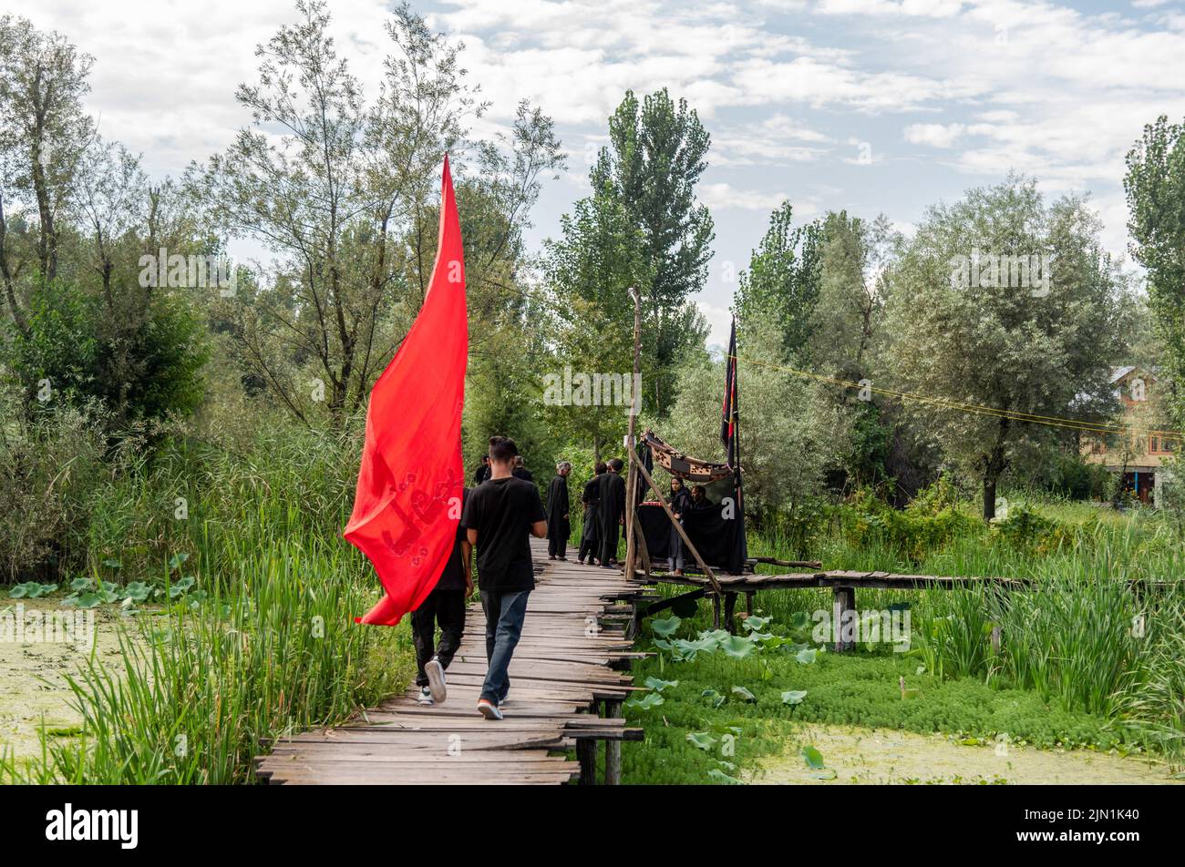 Shia Muslims walk with an Alam along a wooden bridge to participate an ...