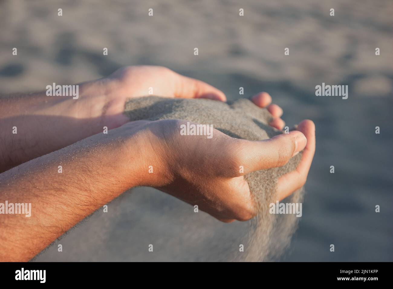 Sand flowing through the fingers of a man's hand, desert sand in the ...