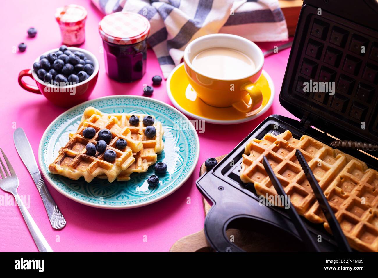 morning and bright breakfast on the pink background. belgian waffles ...