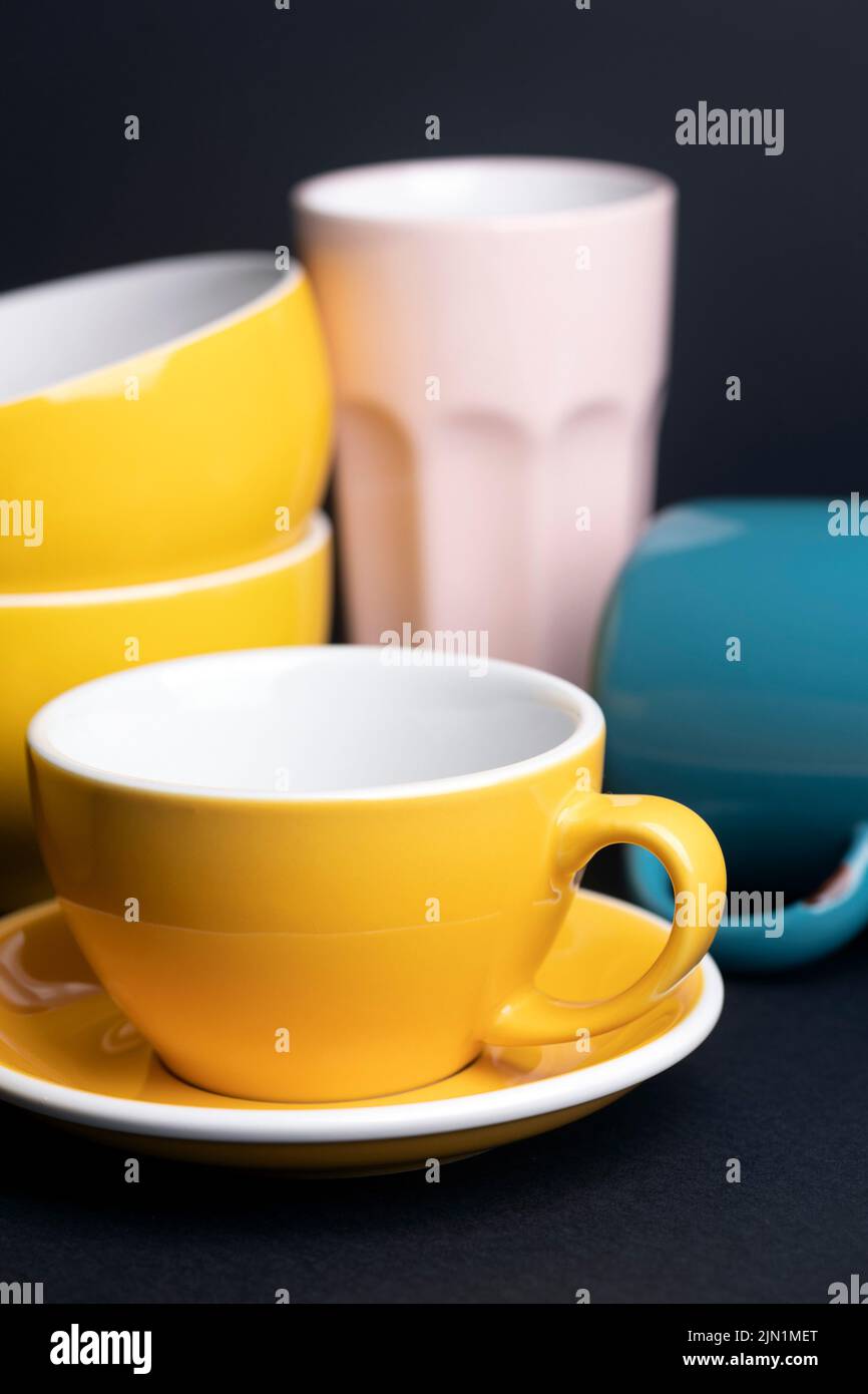 bright ceramics - bowl and cups in yellow, blue, and pink colors on a ...