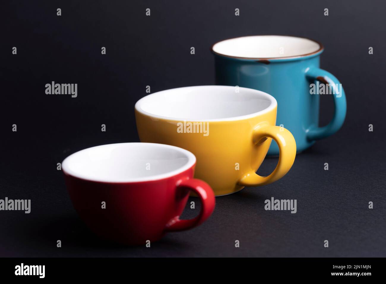 bright ceramics - cups in yellow, blue, red and pink colors on a black ...
