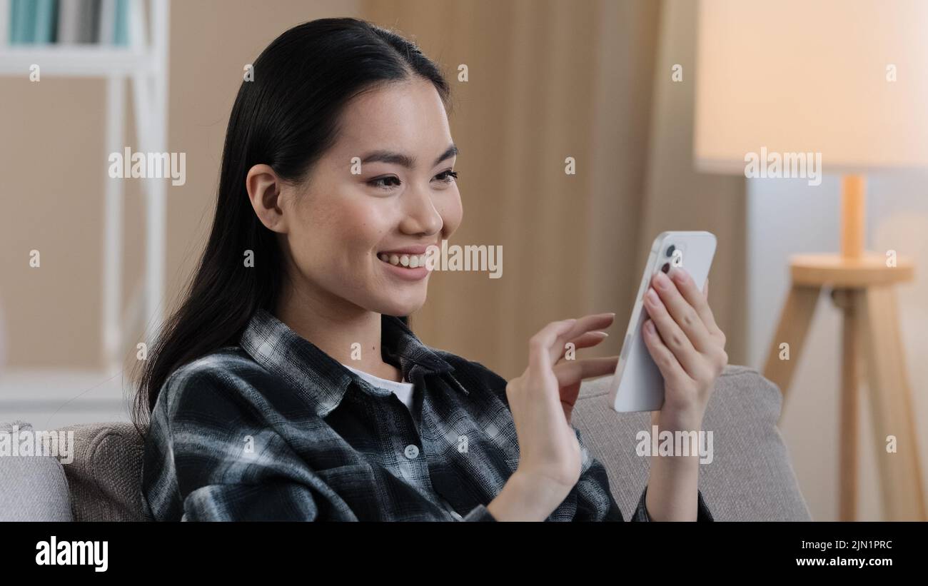 Smiling happy Asian woman typing swipe touchscreen of phone Korean girl ...