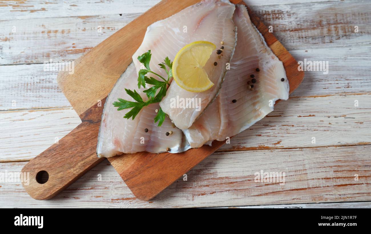 Fresh tilapia fish fillet sliced for steak or salad with herbs spices ...