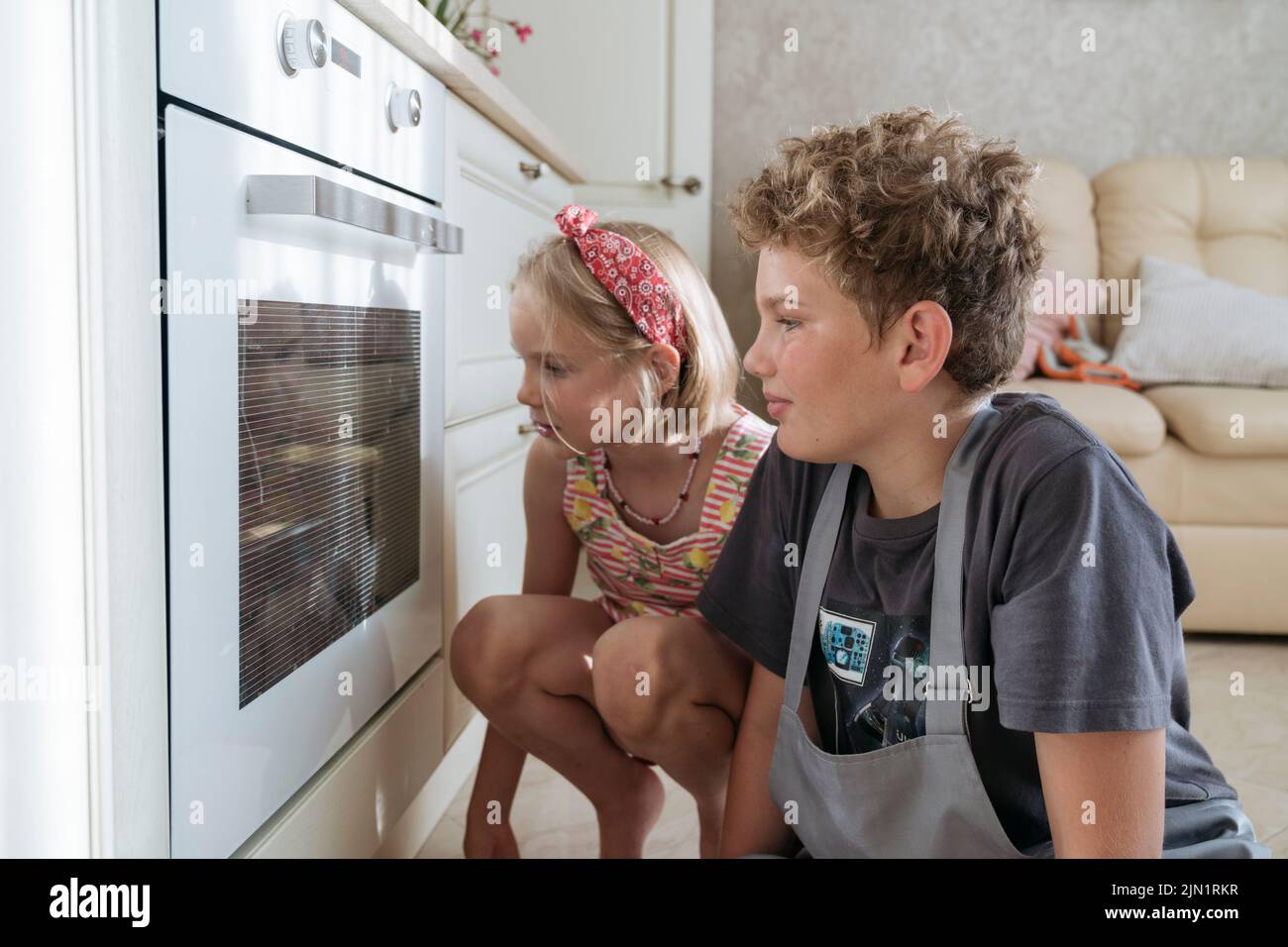 Children look into the oven and wait for the food to be cooked Stock ...