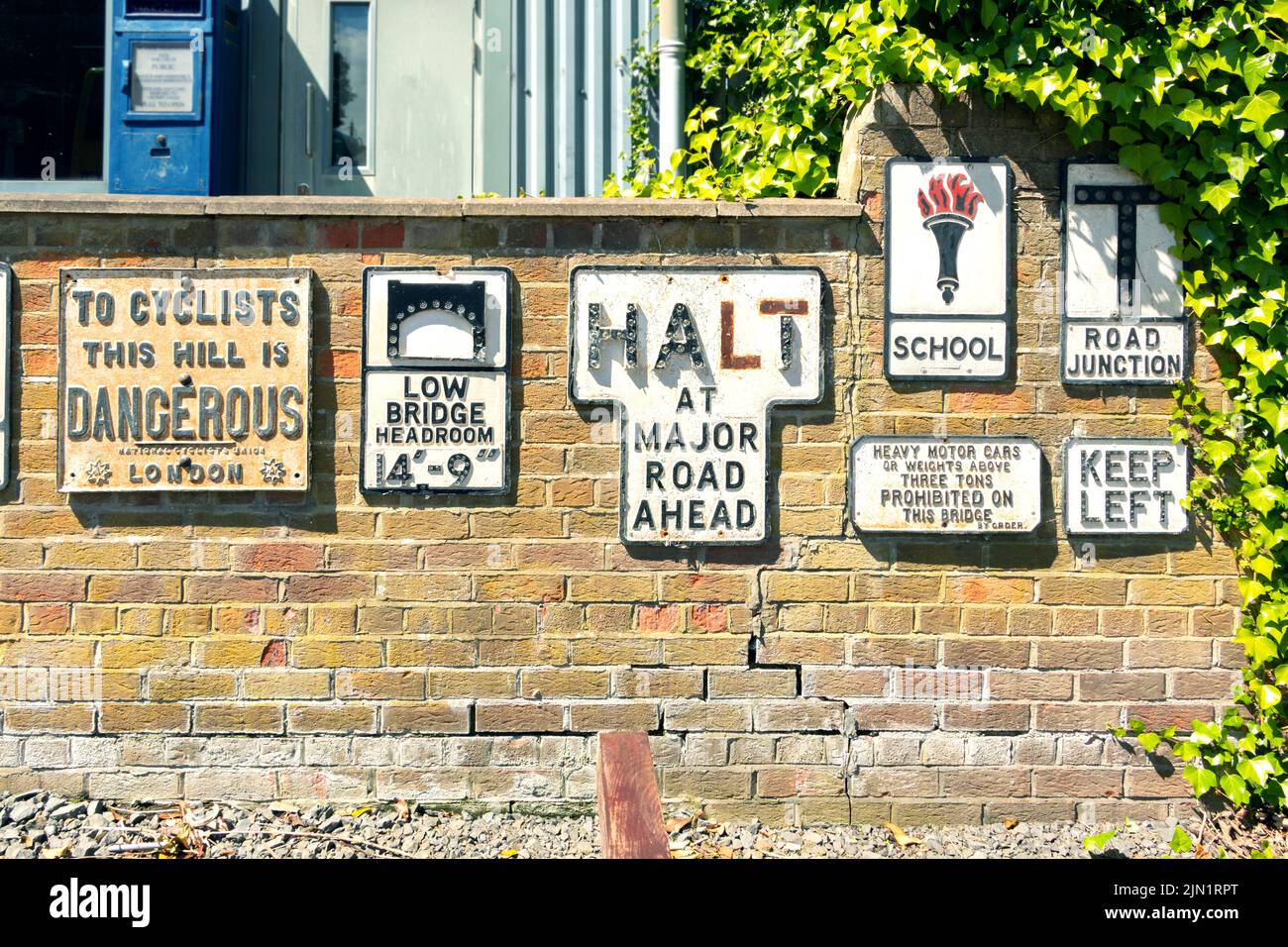 collection of vintage cast metal road signs on brick wall at Beamish ...