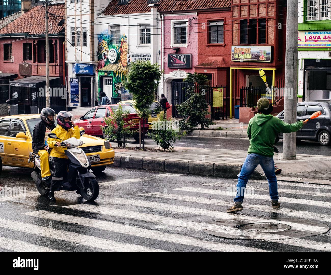 Street entertainer juggling on a pedestrian crossing with an audience ...