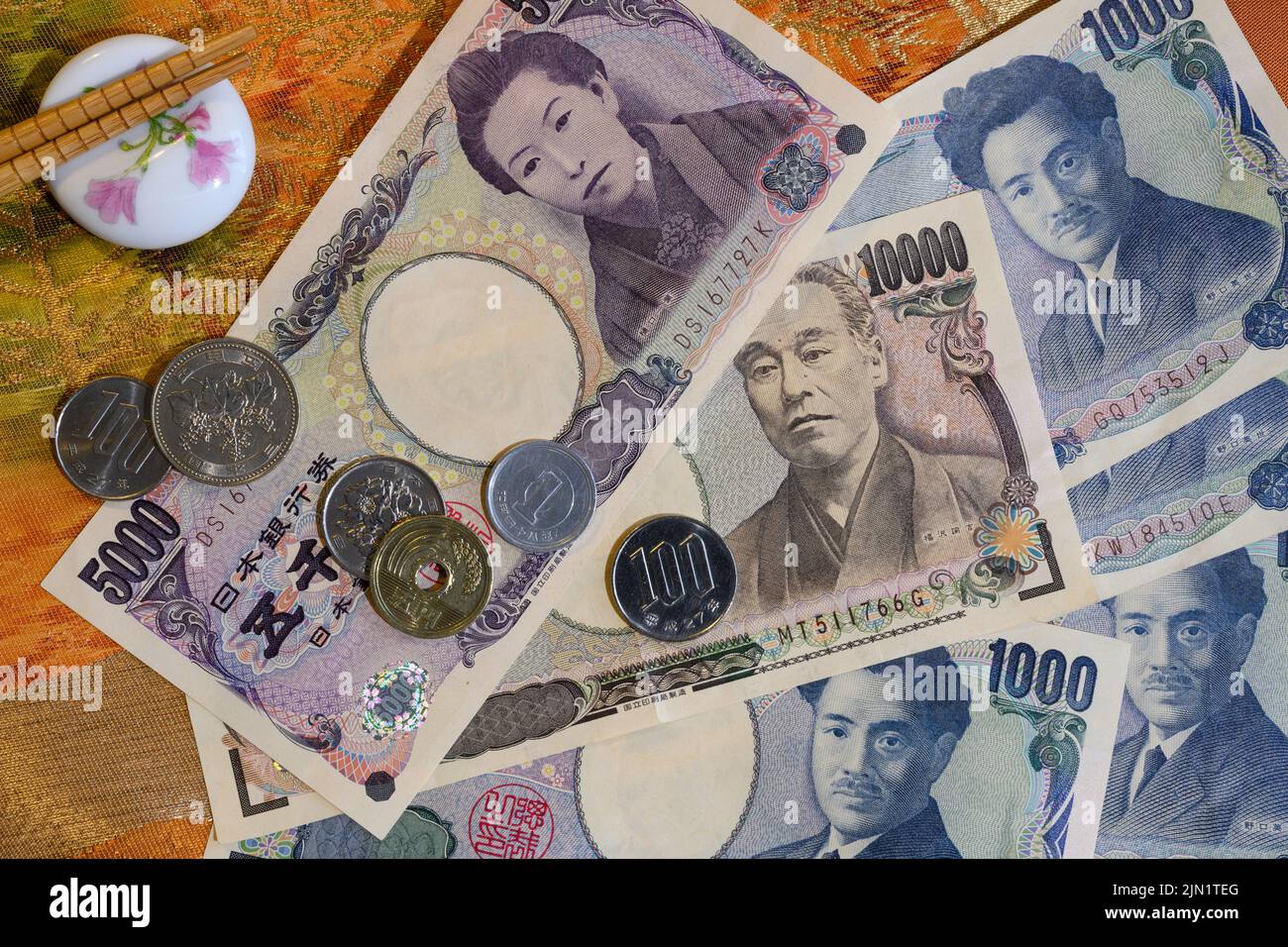 Coins, paper banknotes of Japanese yen and chopsticks on the background ...