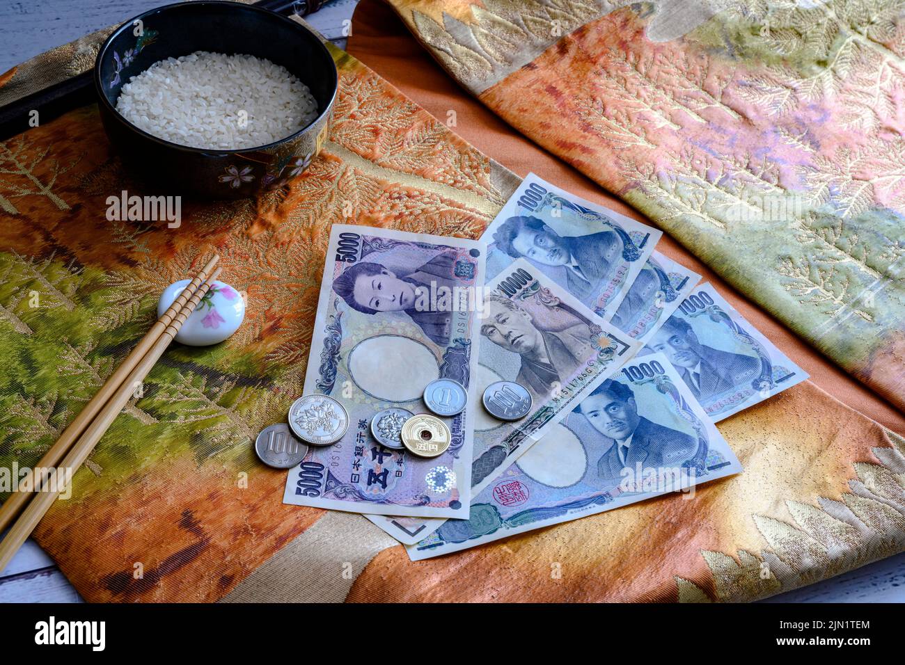Coins and paper banknotes of Japanese yen, and a bowl of rice and ...