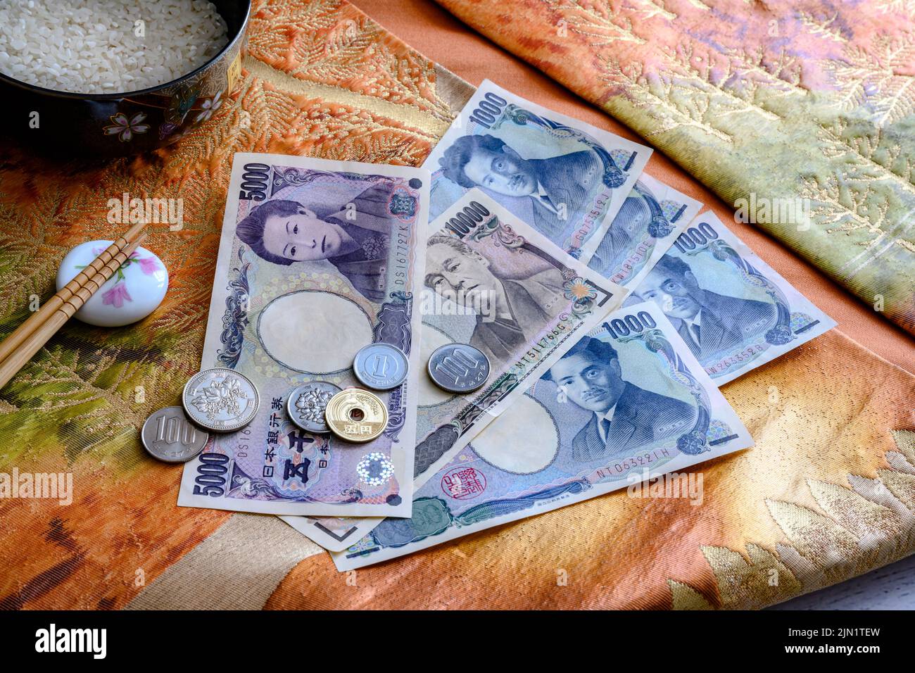 Coins and paper banknotes of Japanese yen, and a bowl of rice and ...
