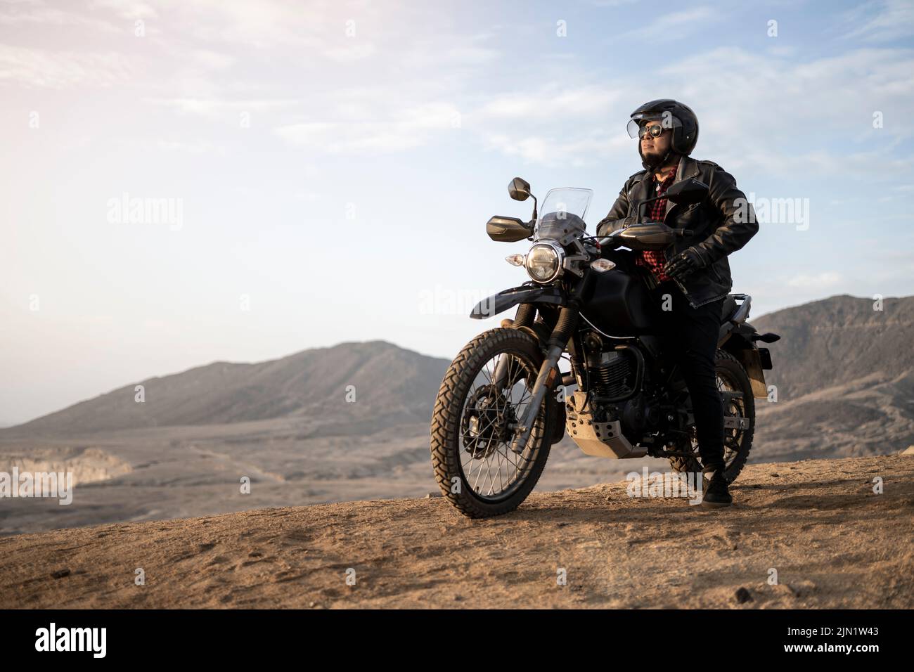 Latin man motorcyclist look at distance. Adventure motorcycle on beach ...