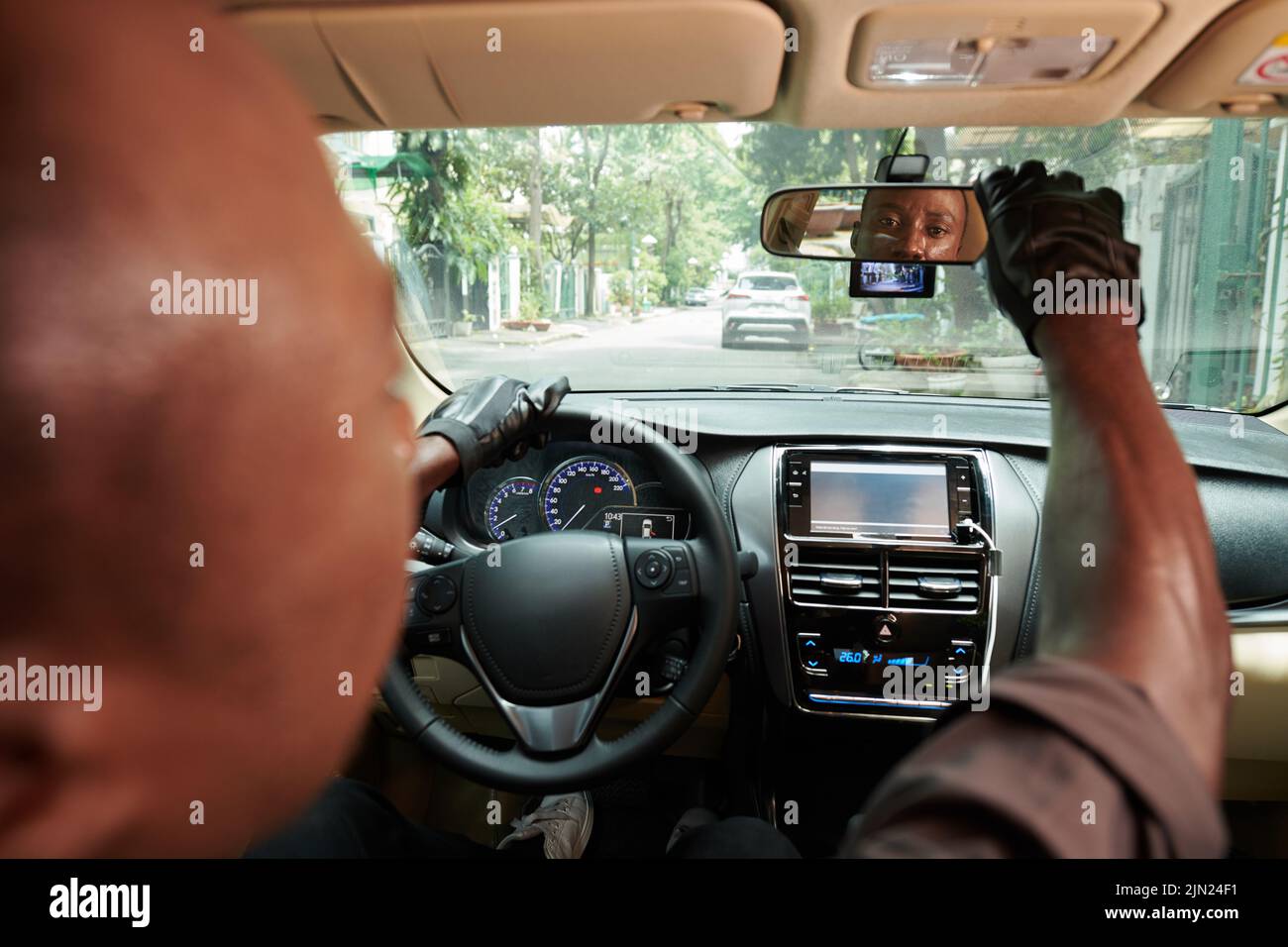 Black car driver adjusting rear view mirror before ride Stock Photo - Alamy