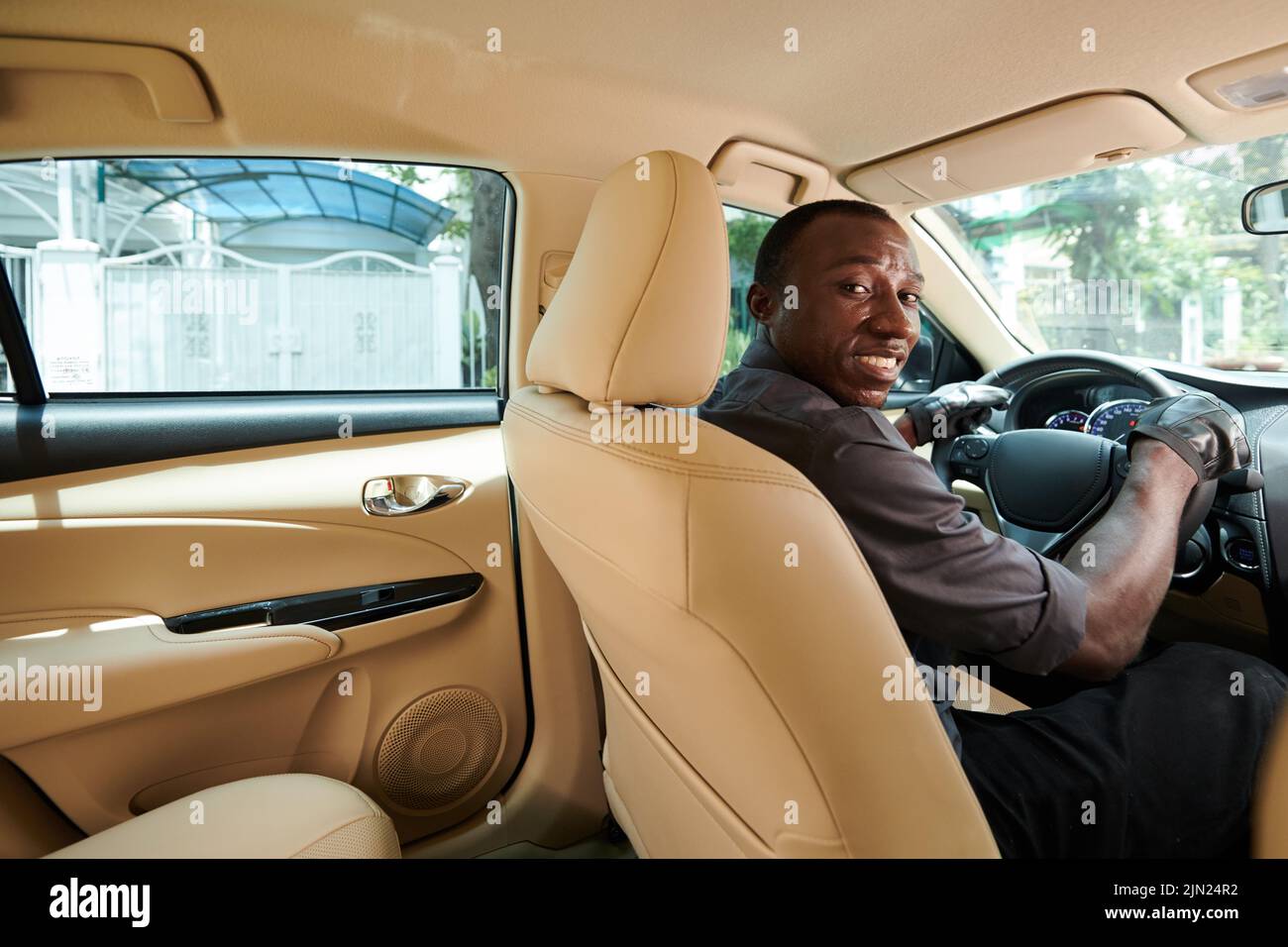 Smiling taxi driver turning back to passenger and asking where to drive ...