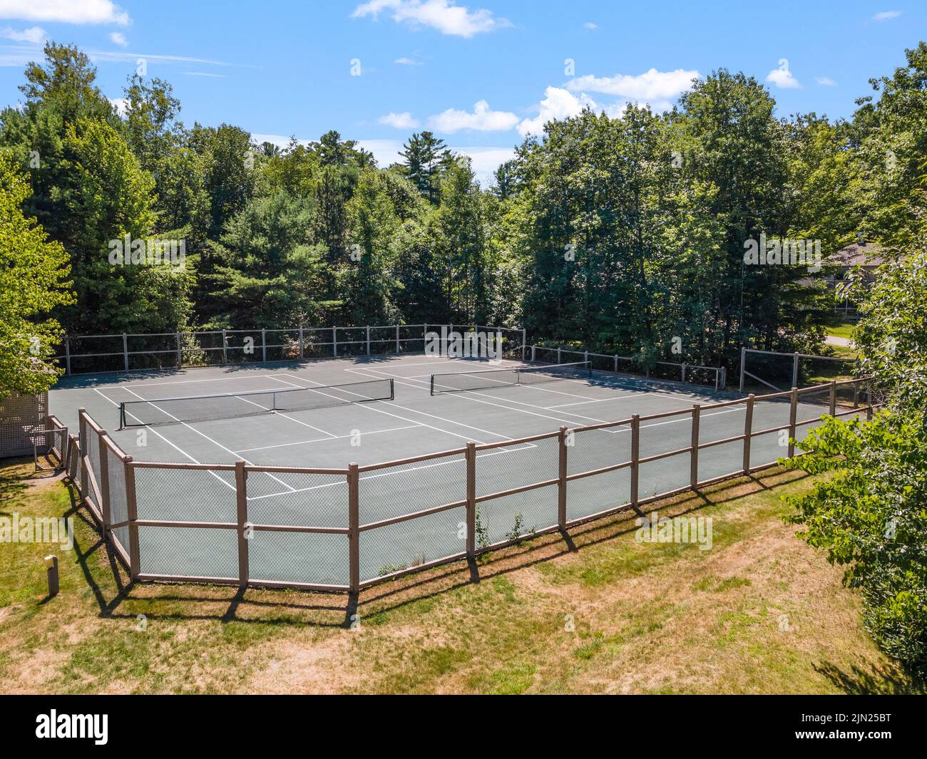 An outdoor tennis court surrounded by green trees Stock Photo - Alamy