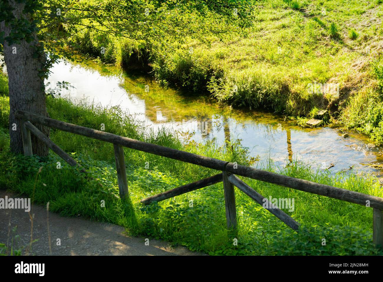 landscape with stream of water and a wooden fence on the road Stock ...