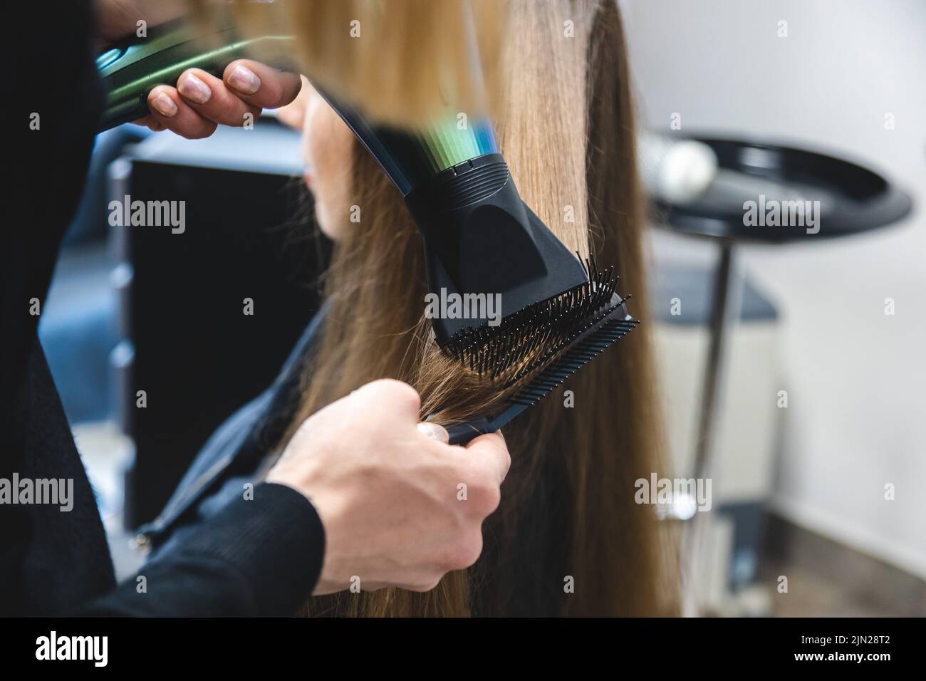 Master woman hairdresser dries the girl's hair with a hairdryer and ...