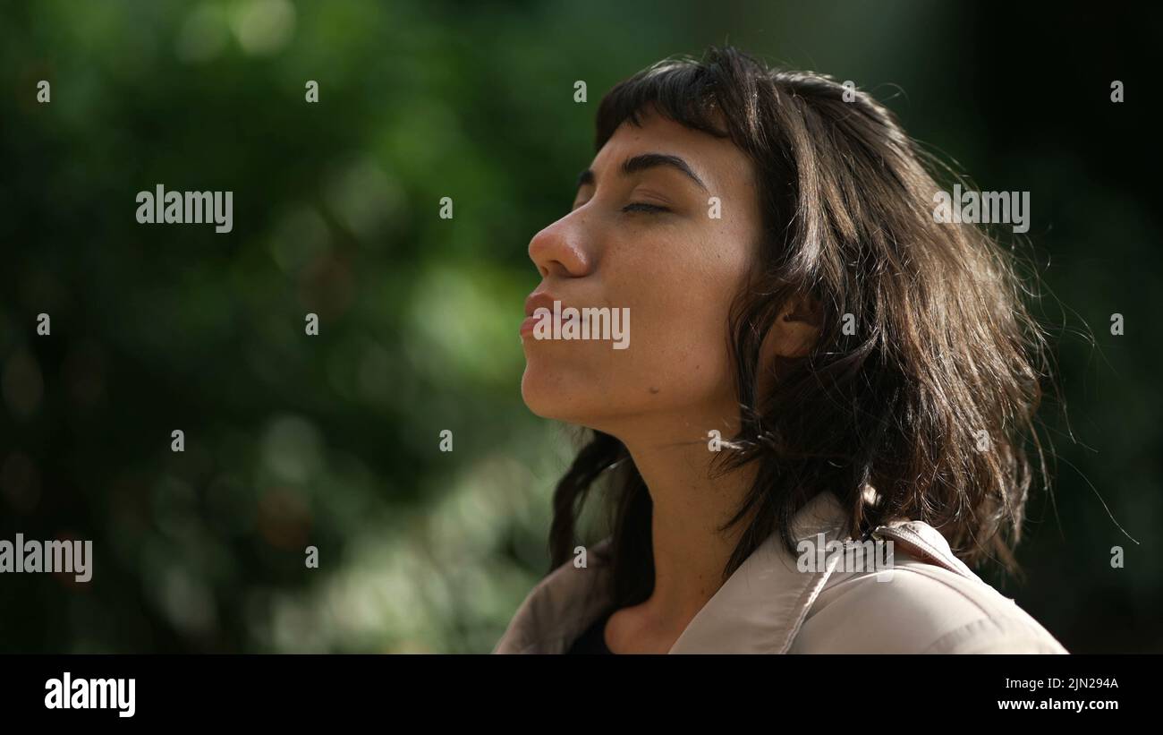 Relaxed young woman with eyes closed standing outside in nature in ...