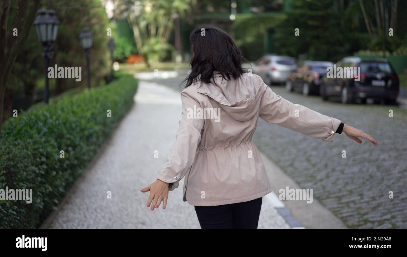 Back of carefree young woman jumping with joy in street flying in the ...