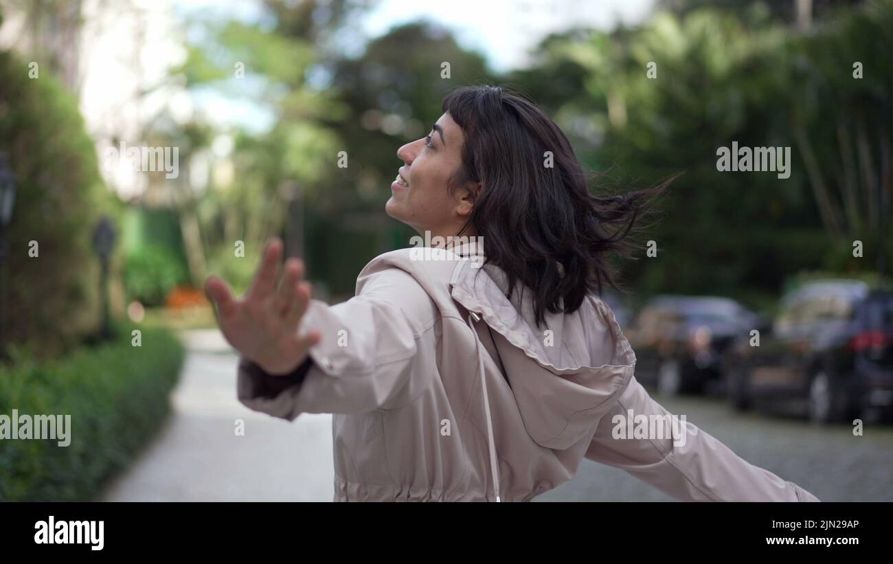 Back of carefree young woman jumping with joy in street flying in the ...