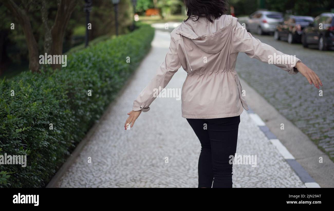Back of carefree young woman jumping with joy in street flying in the ...